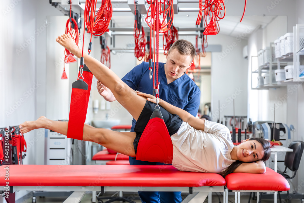 Female patient hanging on suspensions at rehabilitation center. Stock ...