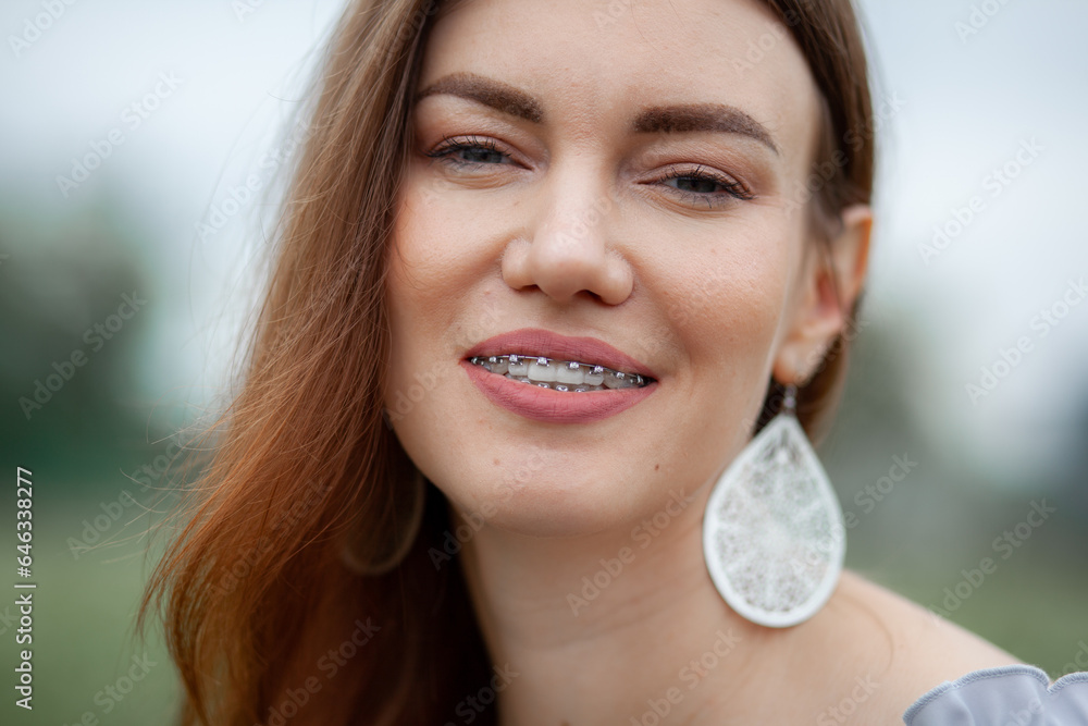 The smile of a young and beautiful girl with braces on her white teeth ...