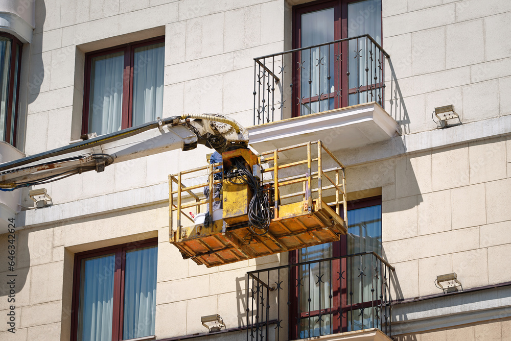 Man paint wall and renovate balcony at height in lifting bucket ...