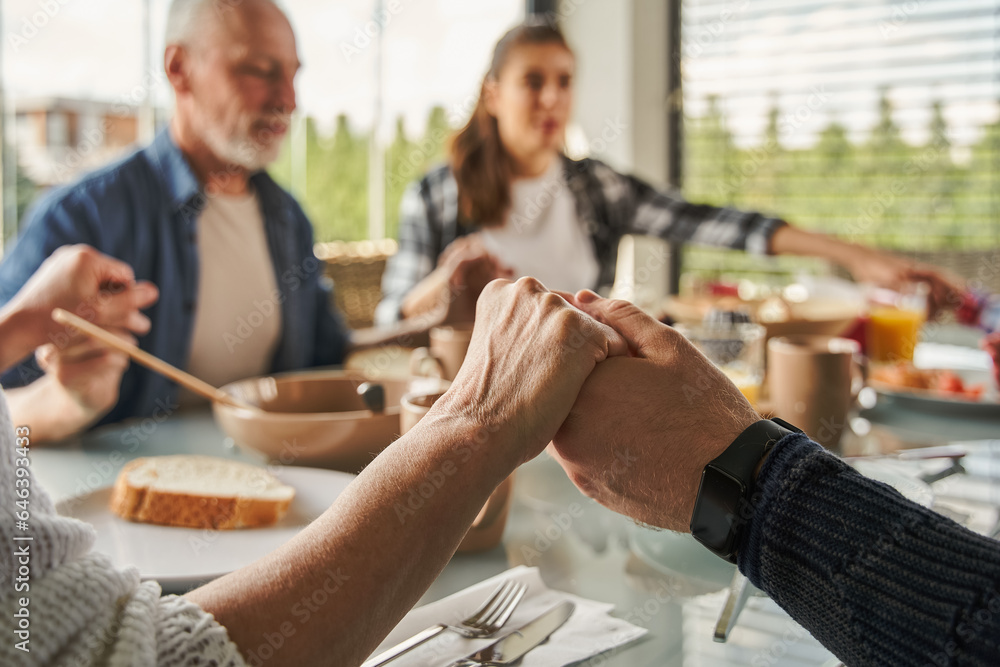Christian family praying before breakfast and holding hands at the ...
