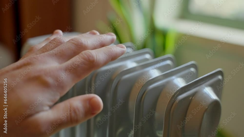 Warm radiator heater indoors for cold winter days hand is warming up ...