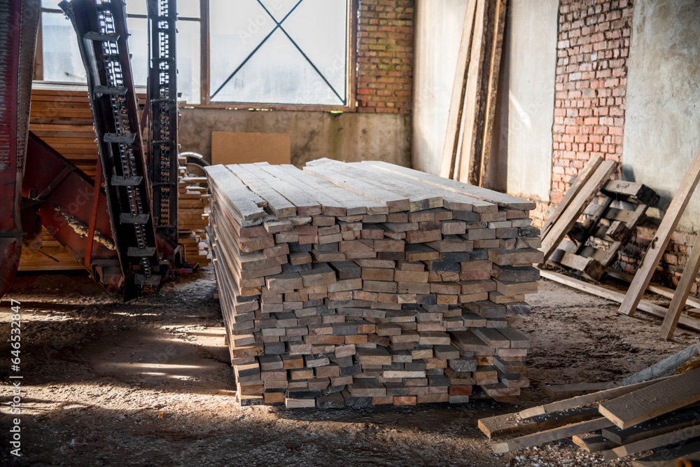 Side view of stack ow wooden pine tree planks lying on floor in sawmill ...
