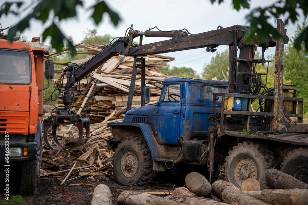 Side view of blue truck with grub bucket standing by wooden planks ...