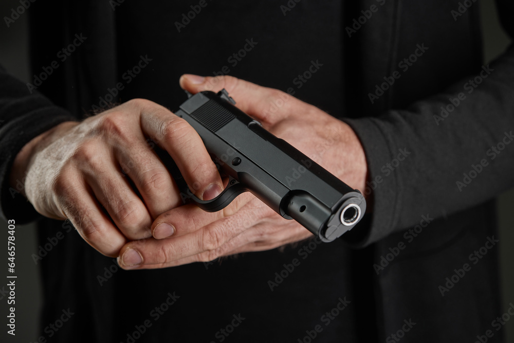 Male hand holding a gun on black background . A gun in a man's hand ...