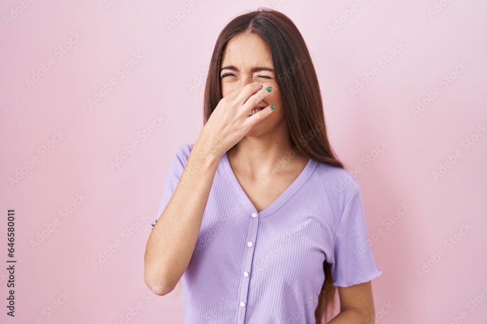 Young hispanic woman with long hair standing over pink background ...