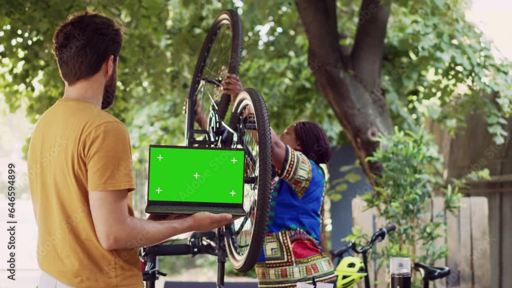 Young man with laptop displaying greenscreen as african american lady ...