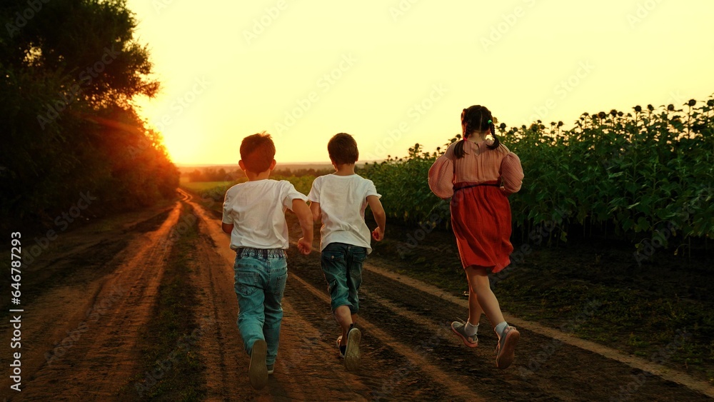 Children play, run through field of sunflowers, friends run at sunset ...