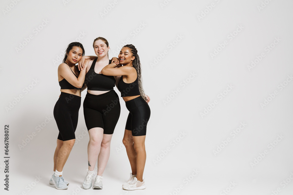 Three smiling women with different body types posing together isolated ...