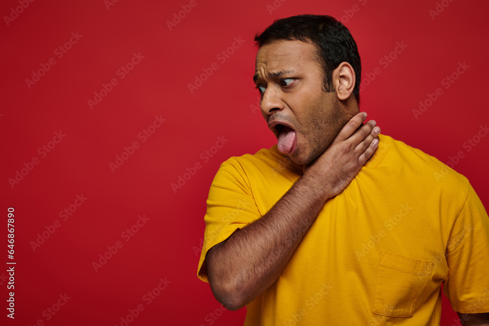 indian man in yellow clothes sticking out tongue while choking on red ...