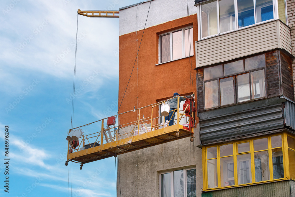 Worker in suspended platform cradle paint building wall. Painter ...