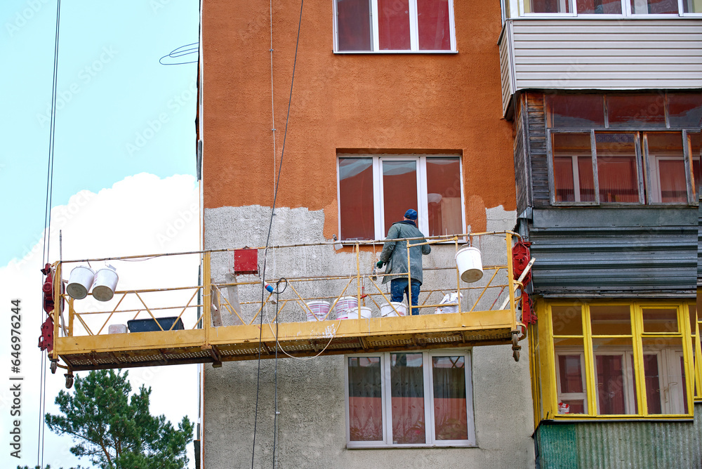 Worker in suspended platform cradle paint building wall. Painter ...