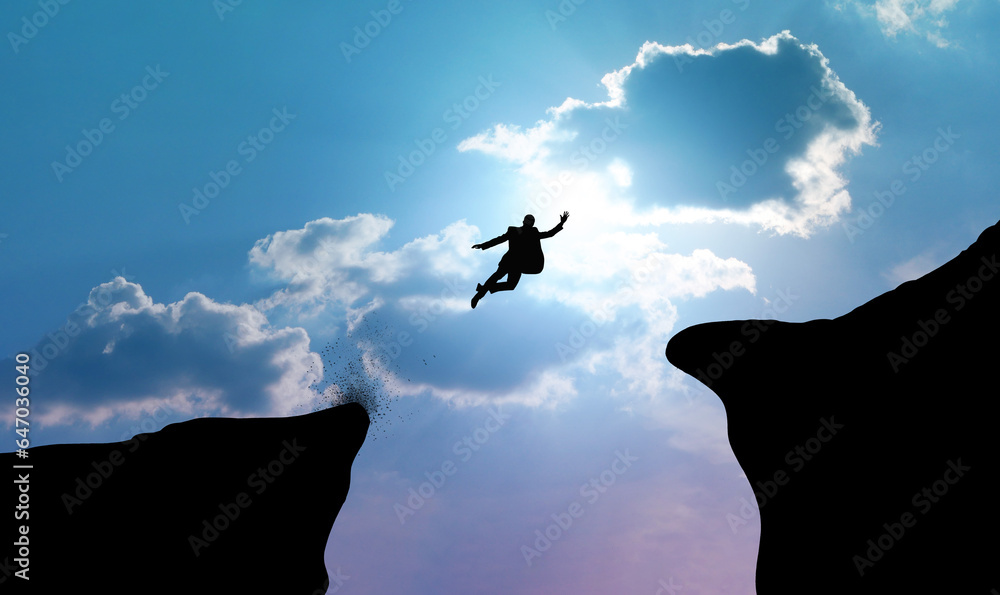 Silhouette of businessman leaping or jumping across two cliffs. Business concepts of decision ...