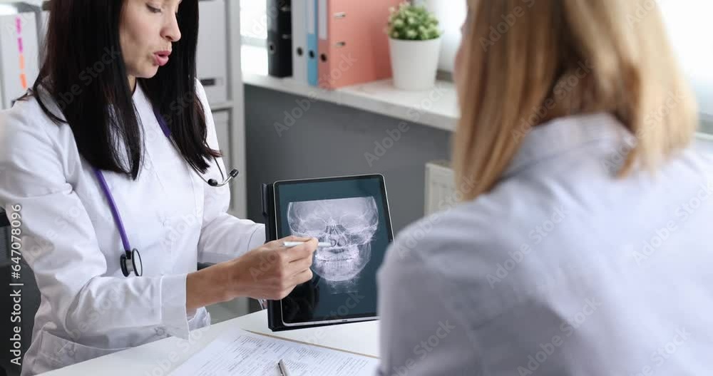 Female doctor and patient at reception are discussing an x-ray of ...