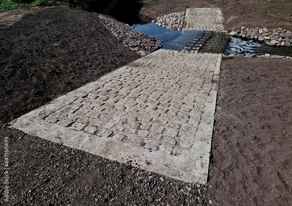 The dirt road leads across a stream that crosses river and continues ...