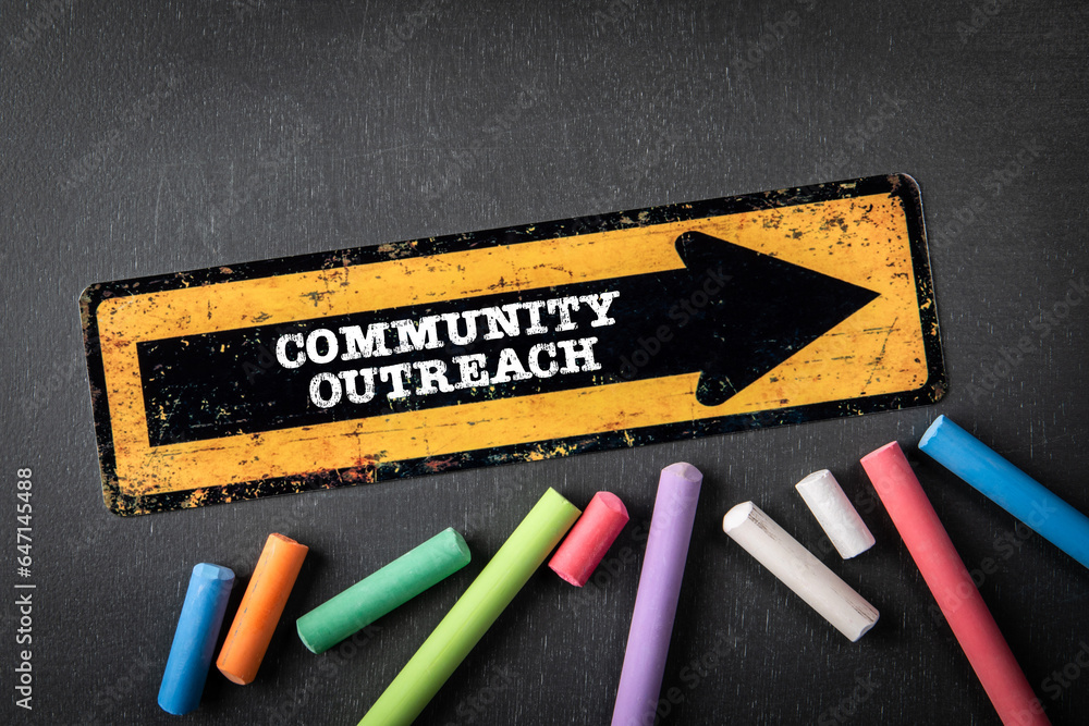COMMUNITY OUTREACH. Yellow directional arrow with text on a dark ...