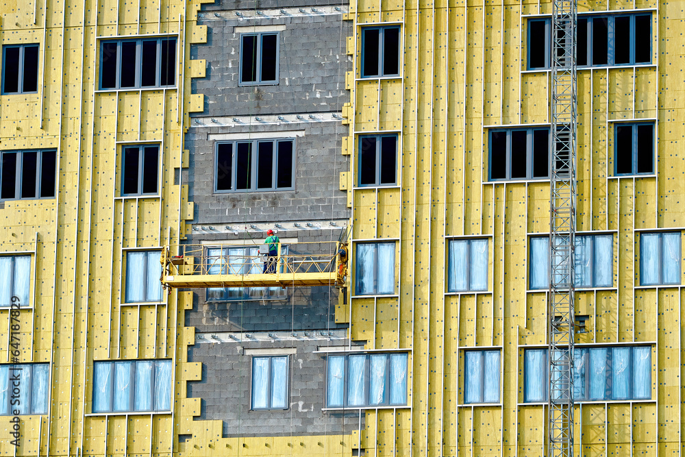 Worker in suspended craddle work with insulation panels and ventilated ...