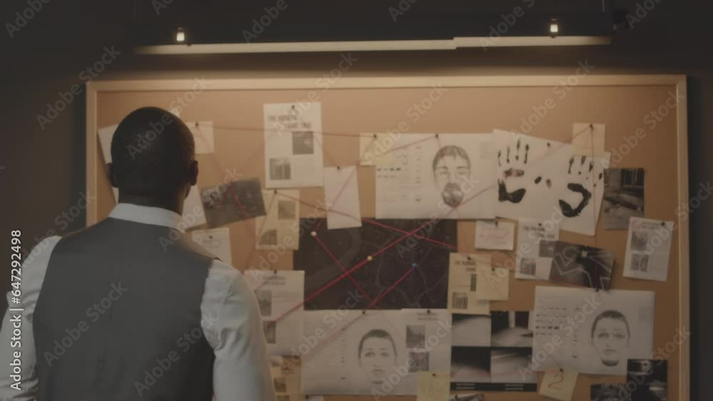Medium back view of African American detective standing by evidence ...