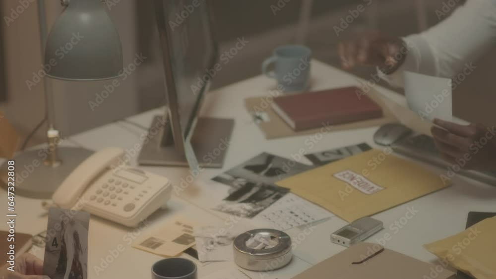 Two multiethnic police detectives discussing pictures from crime scene ...