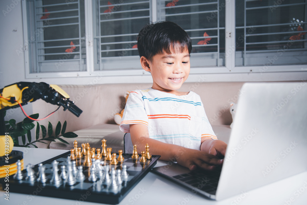 Asian little boy programming code to robot machine arm on laptop for ...