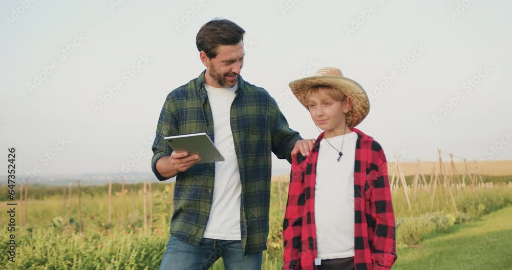 Father and son working on farm. Two farmers man and boy using tablet ...