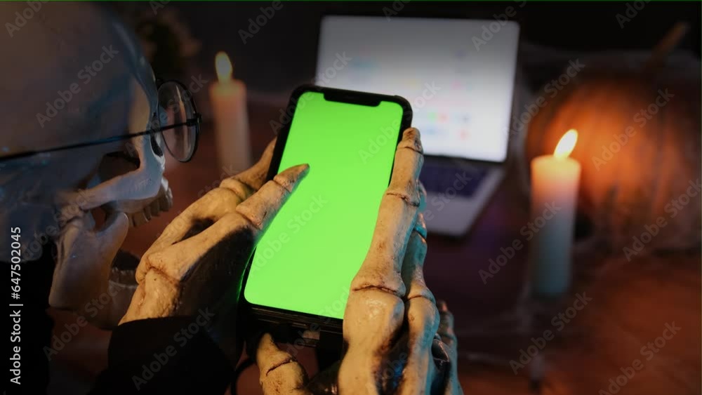 Skull and creepy hands in skeleton costume hold phone with green screen ...