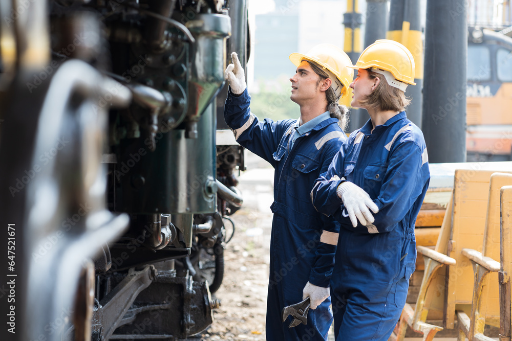 Male and female engineer maintenance locomotive engine, wearing safety ...