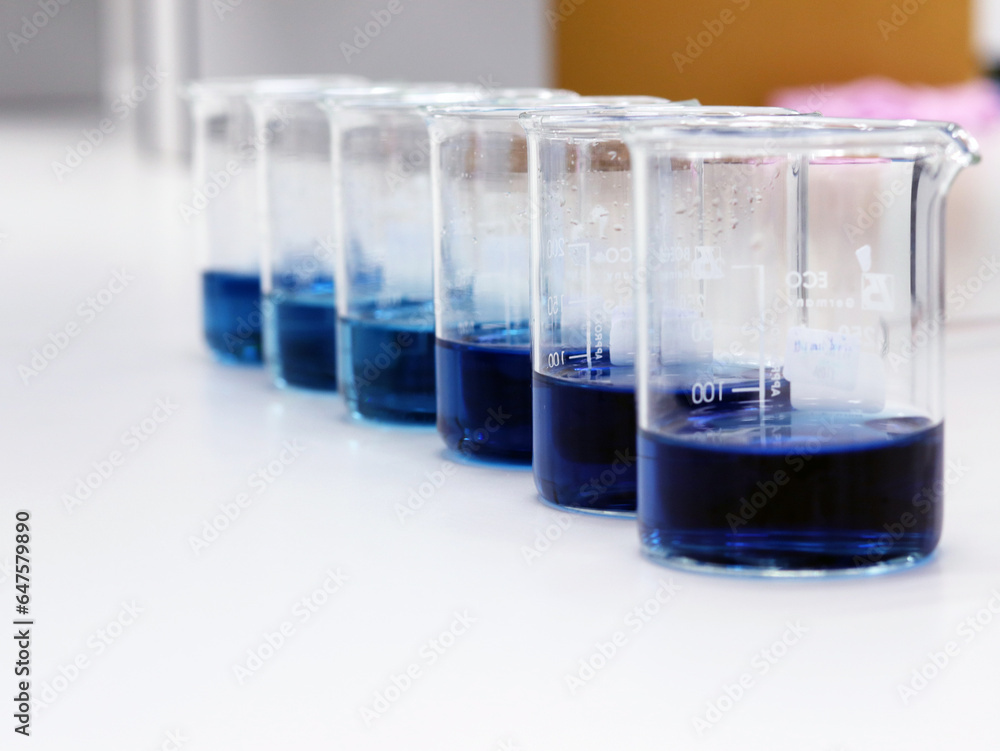 The beakers with blue color range solution on bench laboratory, with ...