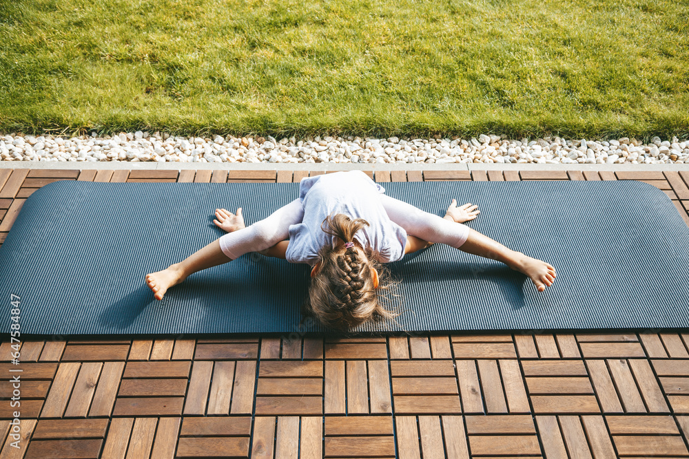 Little girl lying in the Turtle pose or Kurmasana practicing yoga ...