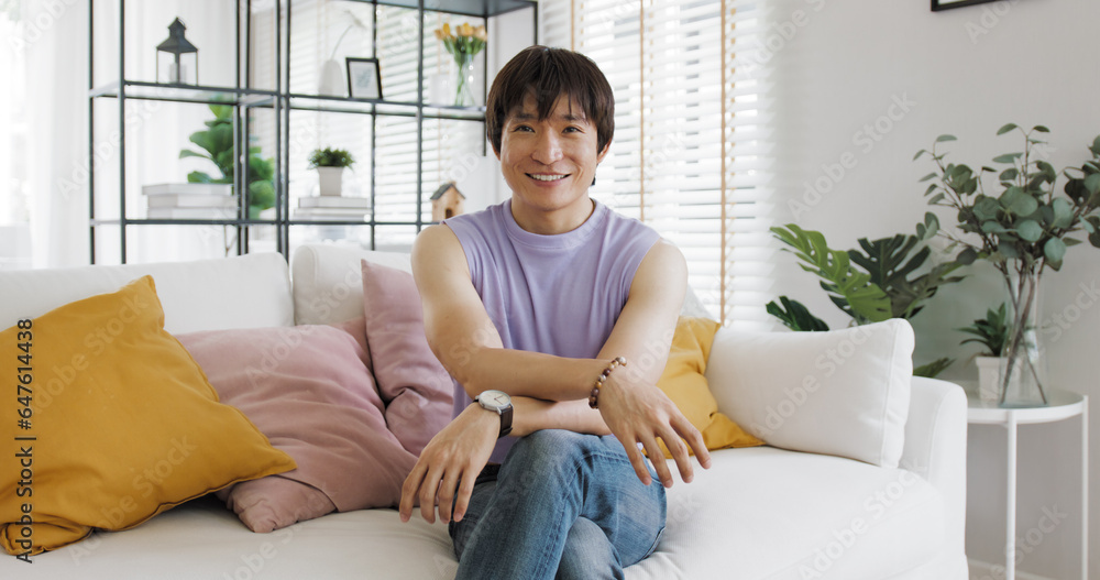 LGBT gay man Gen Z smile look at camera sit easy relax on sofa couch at ...