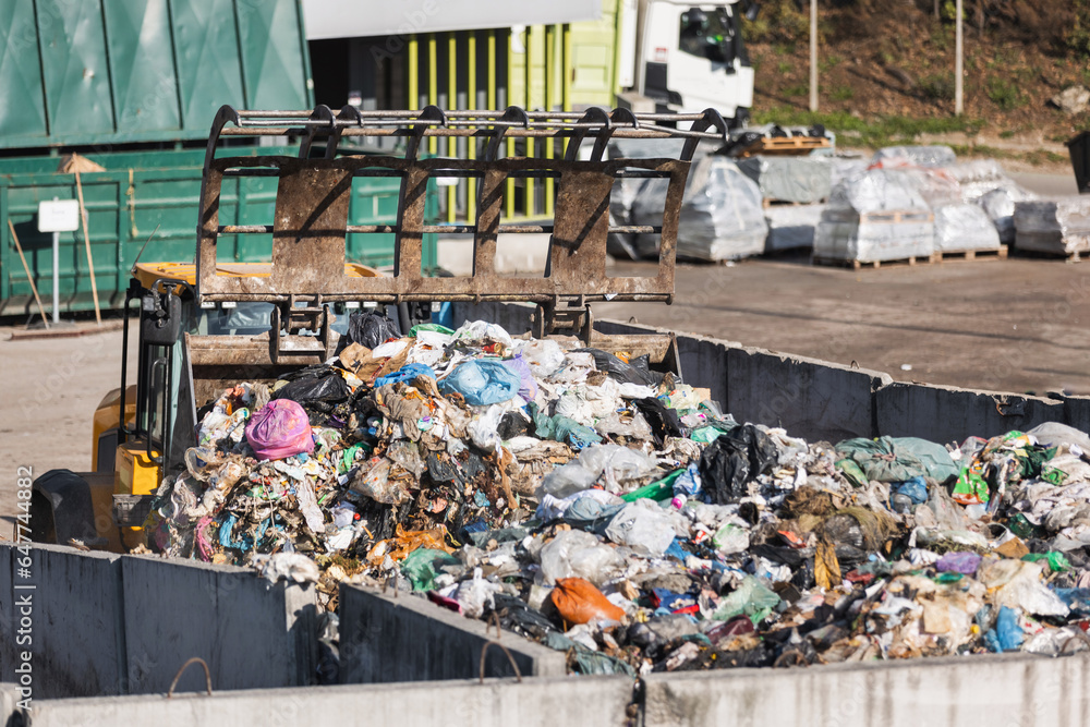 Yellow skid steer loader moving wooden waste material, shaking out a ...