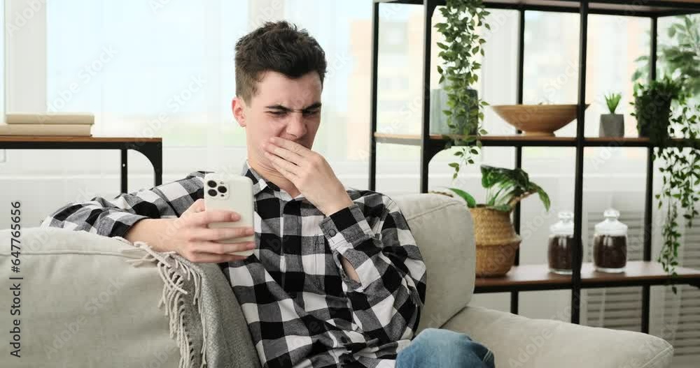 A young man face contorts in strong distaste as he reacts to something ...