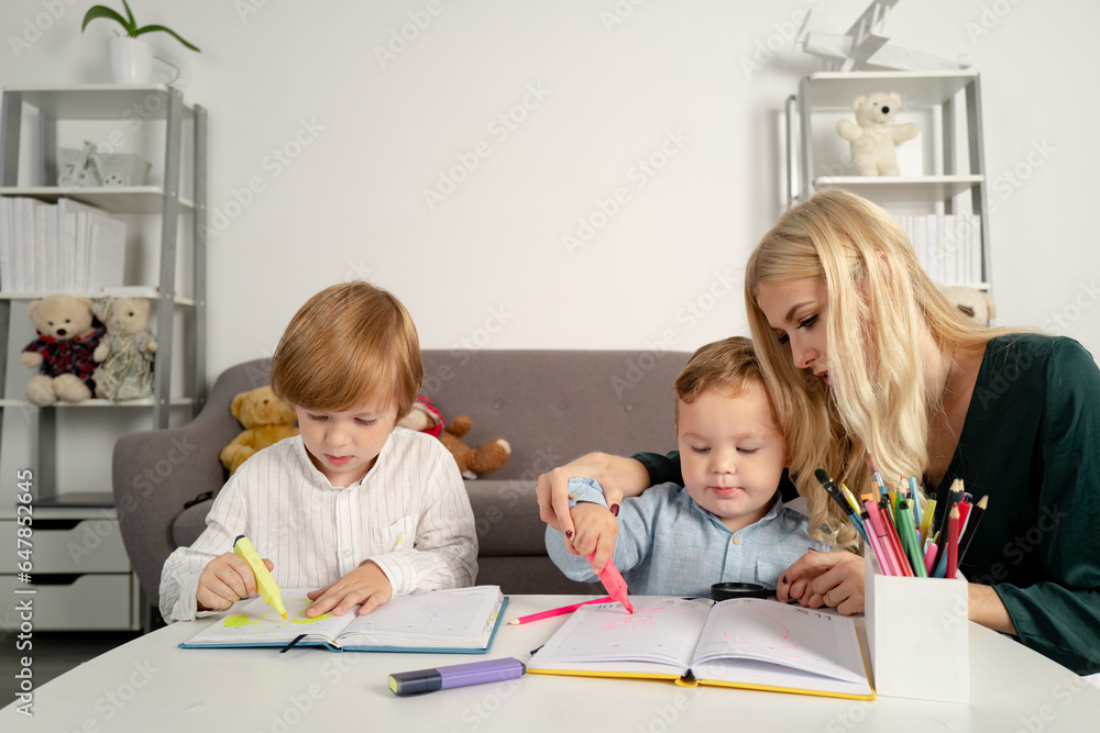 Mother and two son together draw, paint. Mom helps the children boys ...