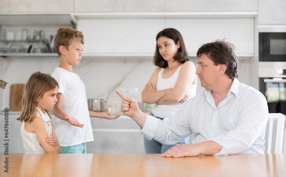 Angry parents scolding two children standing in front of them ...