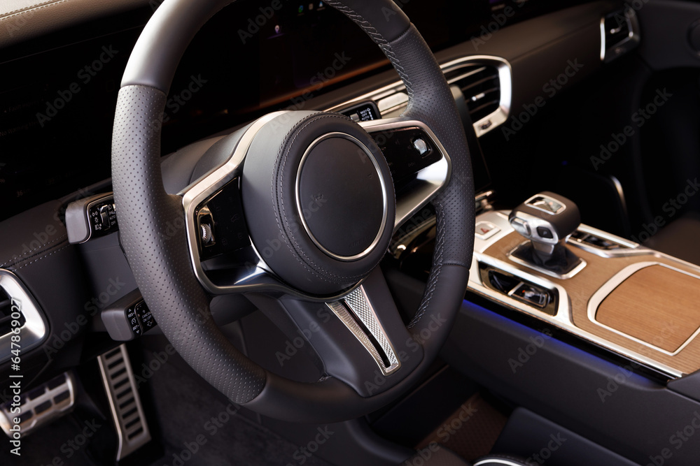 focus on the steering wheel in the interior of a luxury car with wood ...