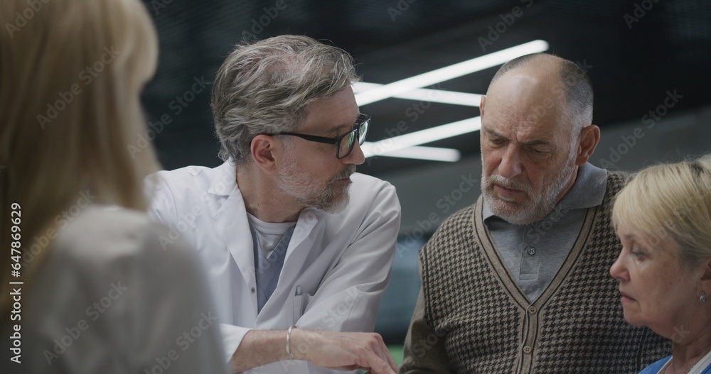 Elderly couple stand near reception desk in medical center waiting room ...
