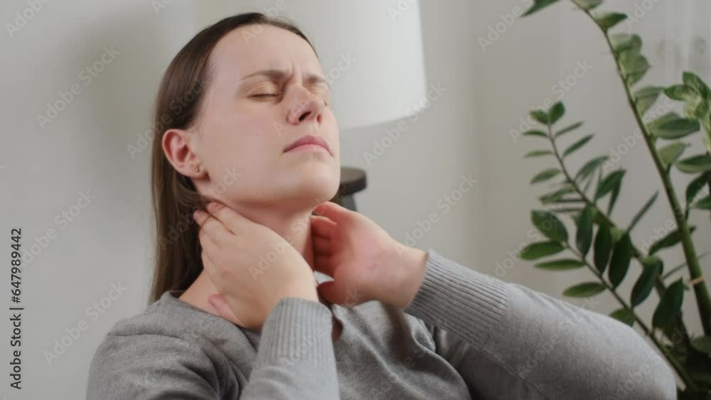 Unhappy young female sitting on couch touch neck suffer from painful ...
