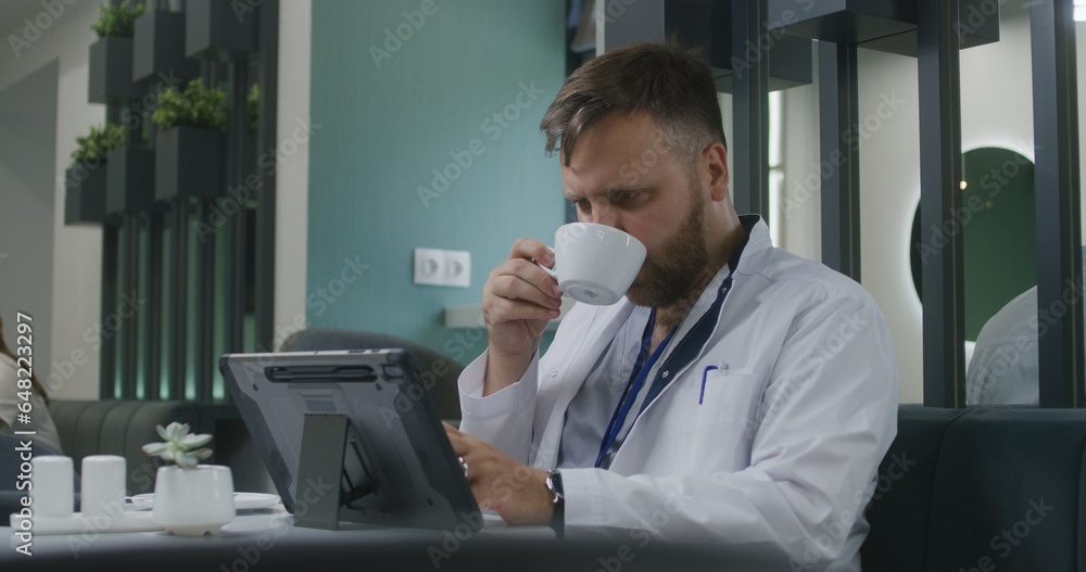 Foto Stock Adult doctor sits in hospital cafeteria and drinks coffee ...