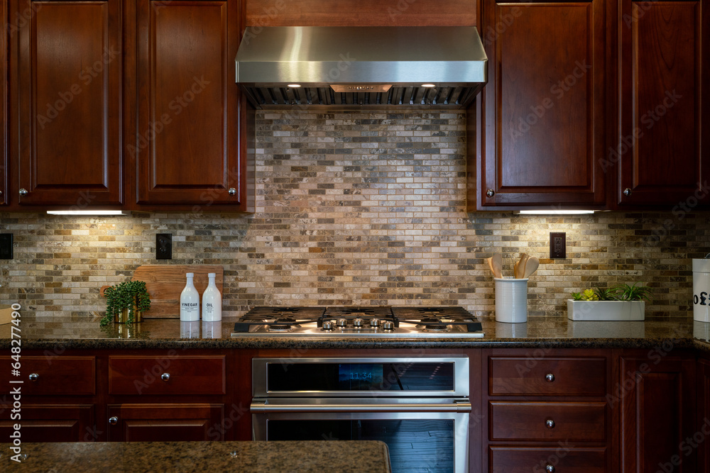 Kitchen details of granite counter, gas stove top, textured tile ...