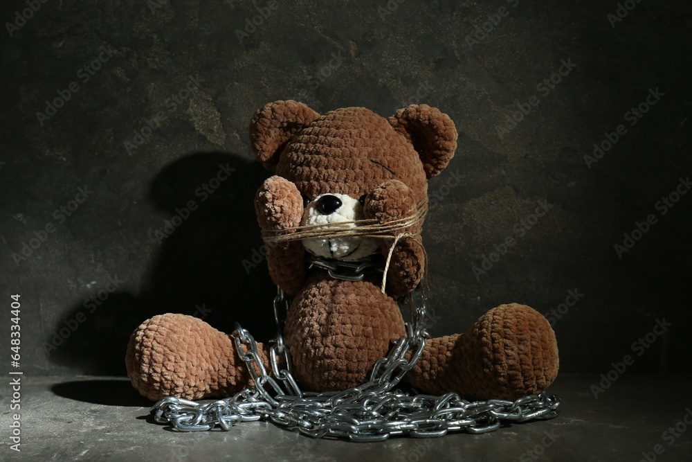 Stop child abuse. Chained toy bear covering eyes on dark grey ...
