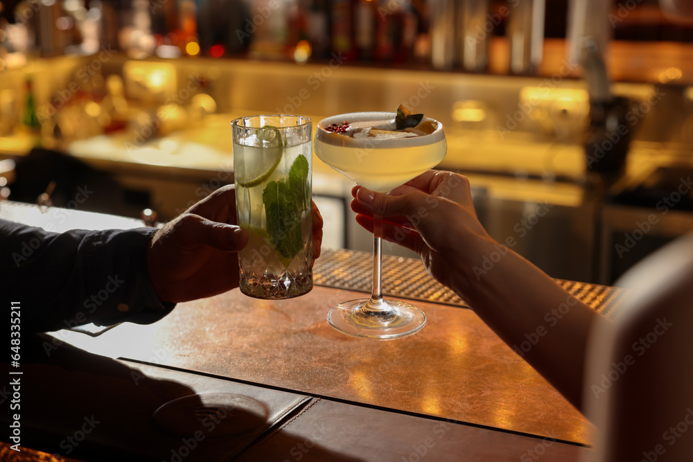 People clinking glasses with fresh cocktails at bar counter, closeup ...