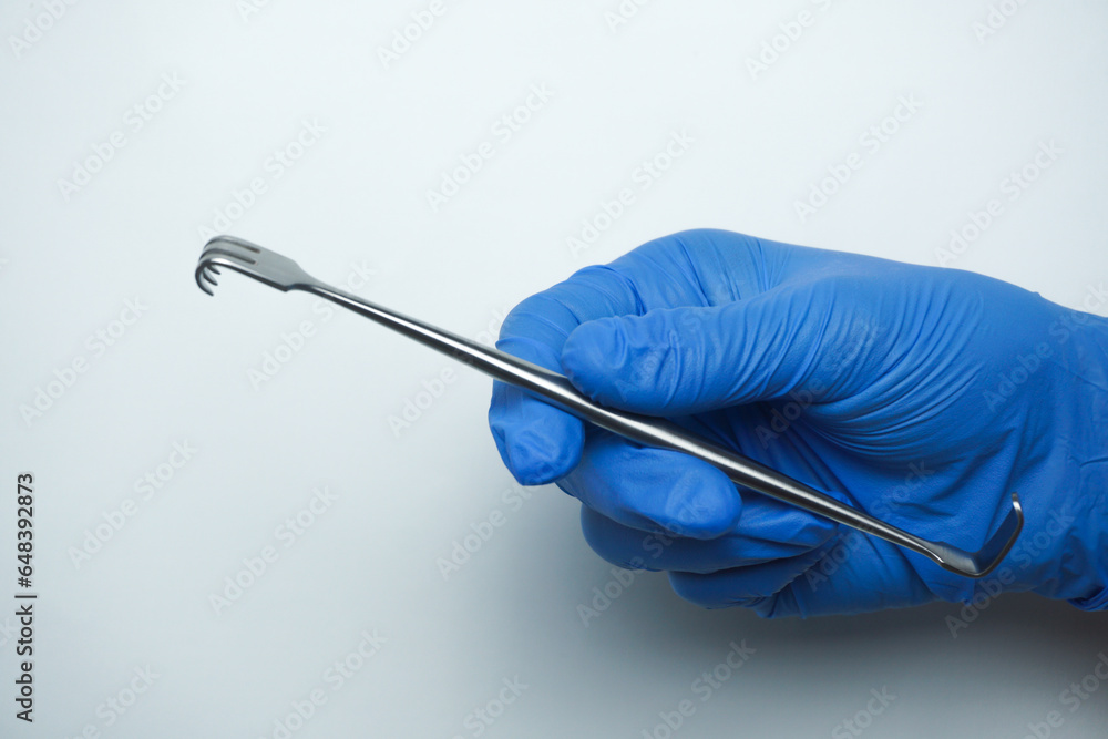 Doctor wearing blue gloves holding sharp Senn-Miller Retractor is a ...