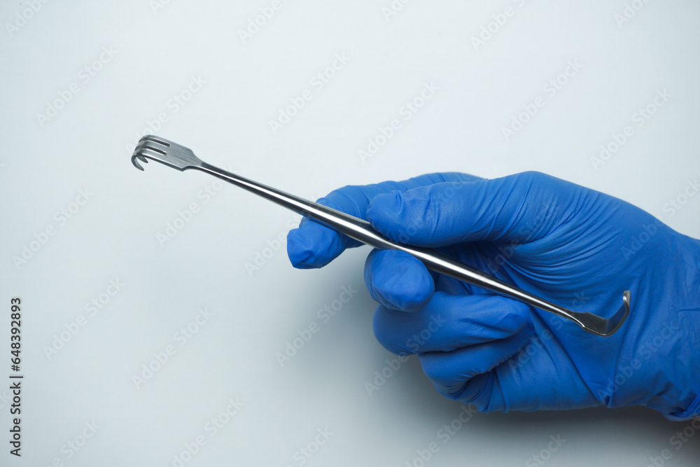 Doctor wearing blue gloves holding sharp Senn-Miller Retractor is a ...