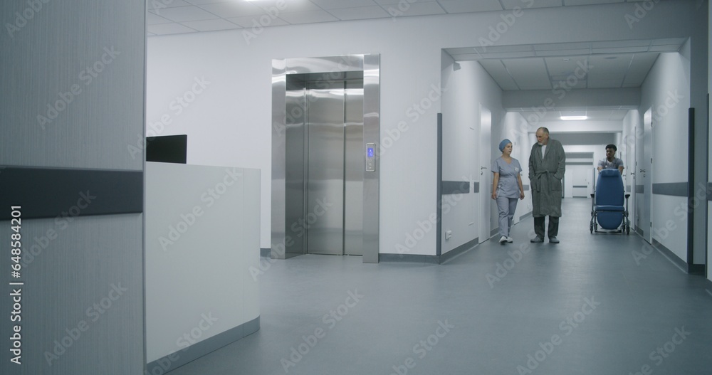 Nurse with old patient wait for elevator in medical center hallway ...