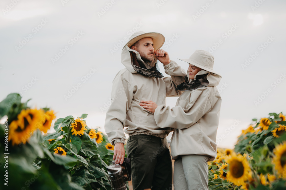 Young beekeepers work with bees in the apiary and eat honey.A young ...