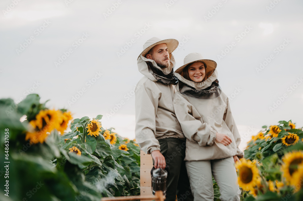 Young beekeepers work with bees in the apiary and eat honey.A young ...