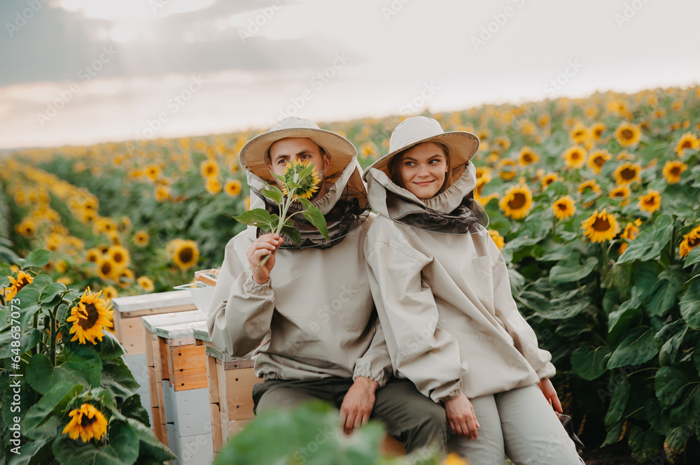 Young beekeepers work with bees in the apiary and eat honey.A young ...
