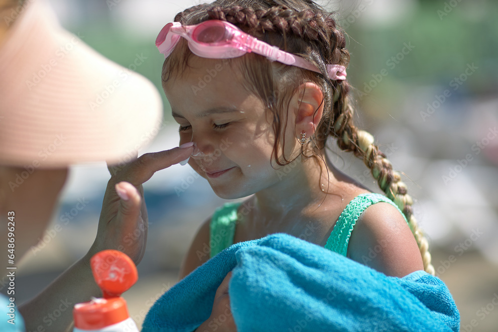the mother applies sunscreen lotion to the little girl's skin. Skin ...