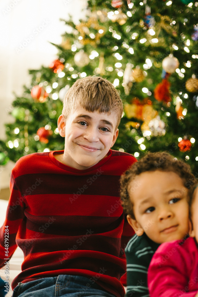 Smiling happy tween with siblings at Christmas with lights and trees ...