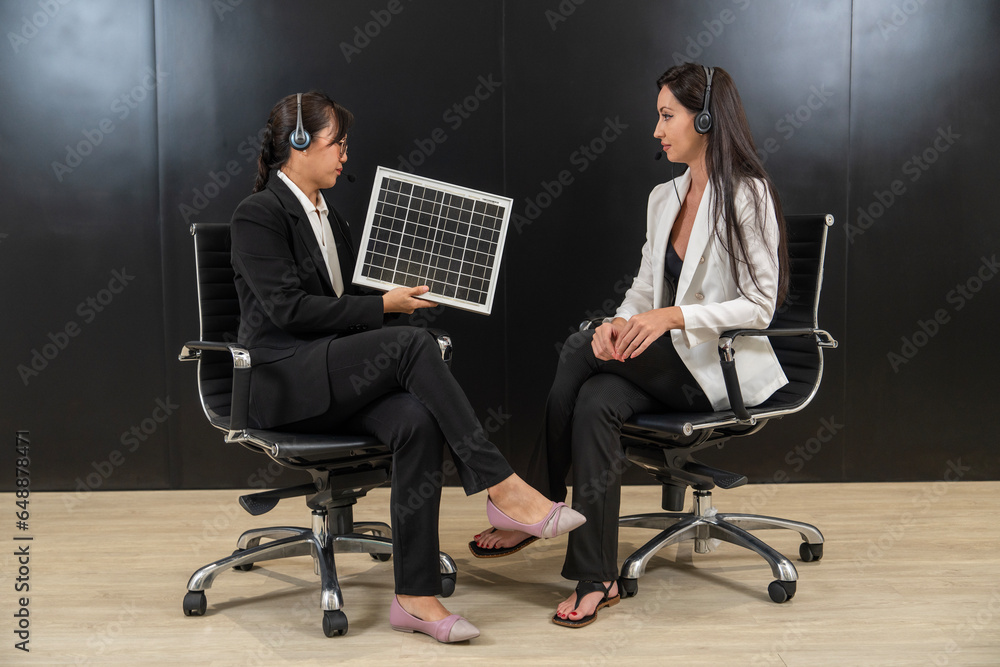 Asian woman wearing glasses, holding a solar cell panel, interviewing a ...