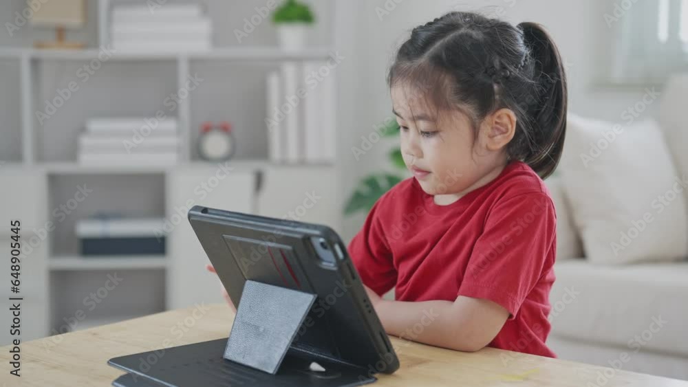 Asian child girl looking using and touch tablet display screen. Baby ...